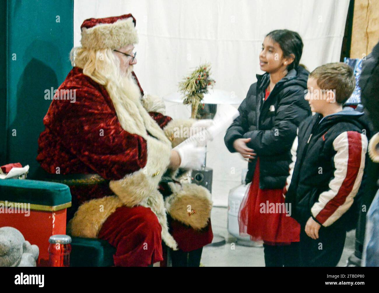A child hands Santa Claus her Christmas list in the Artisan Barn at the ...