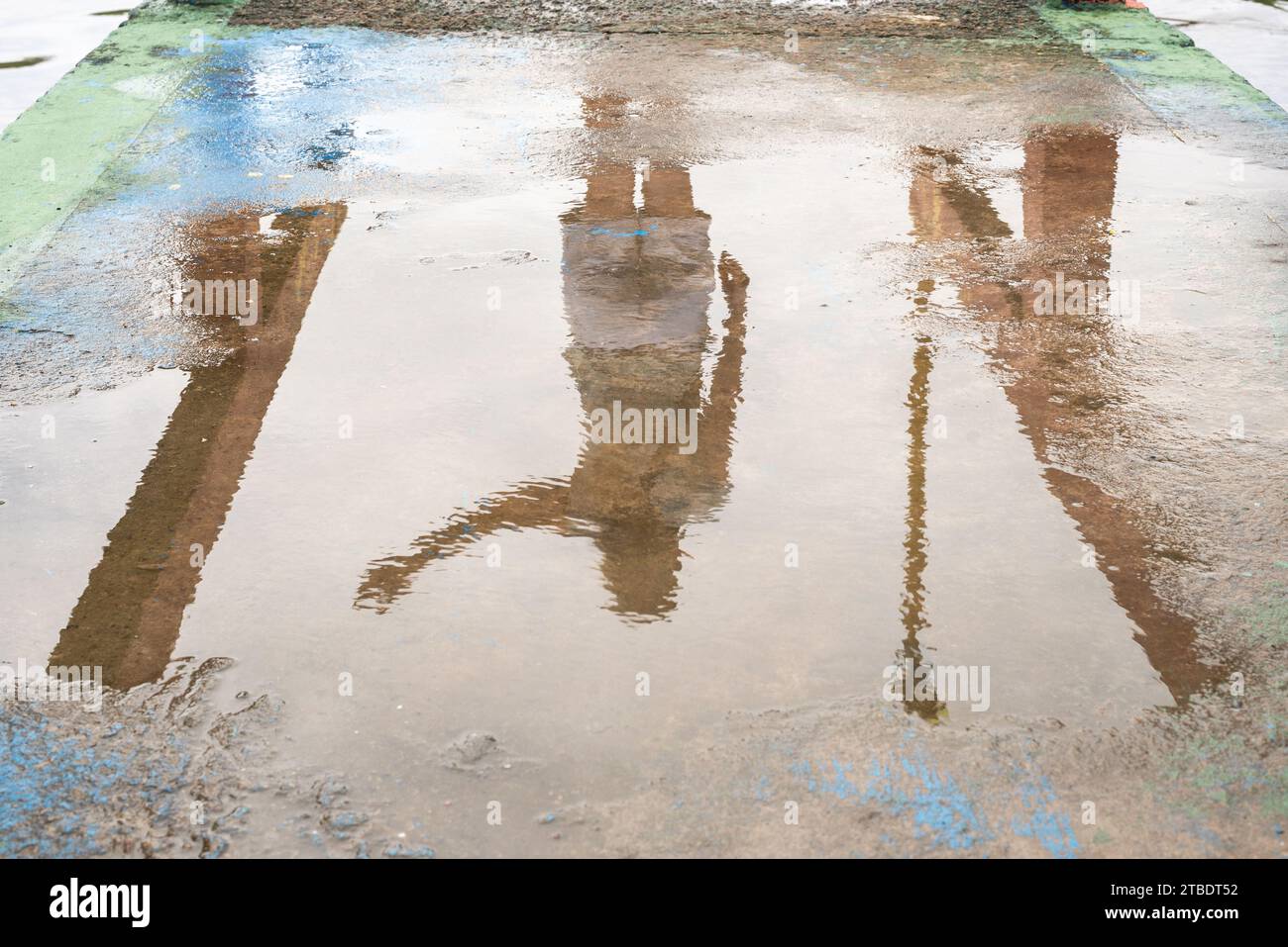 Reflection of an unidentified person in the puddle of water on the ...