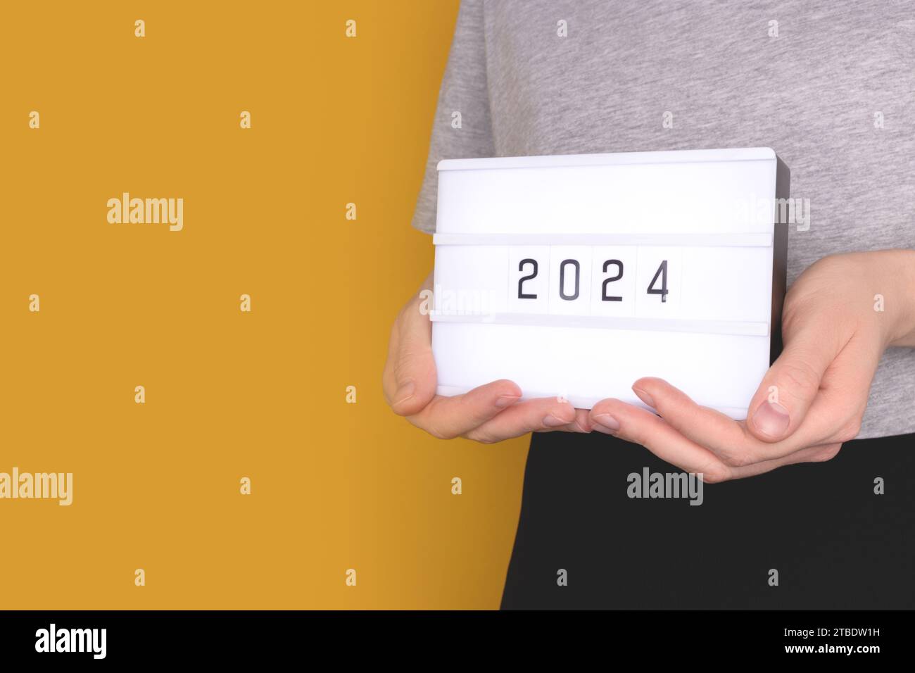 Female hands hold lightbox with 2024 numbers in front of yellow ...