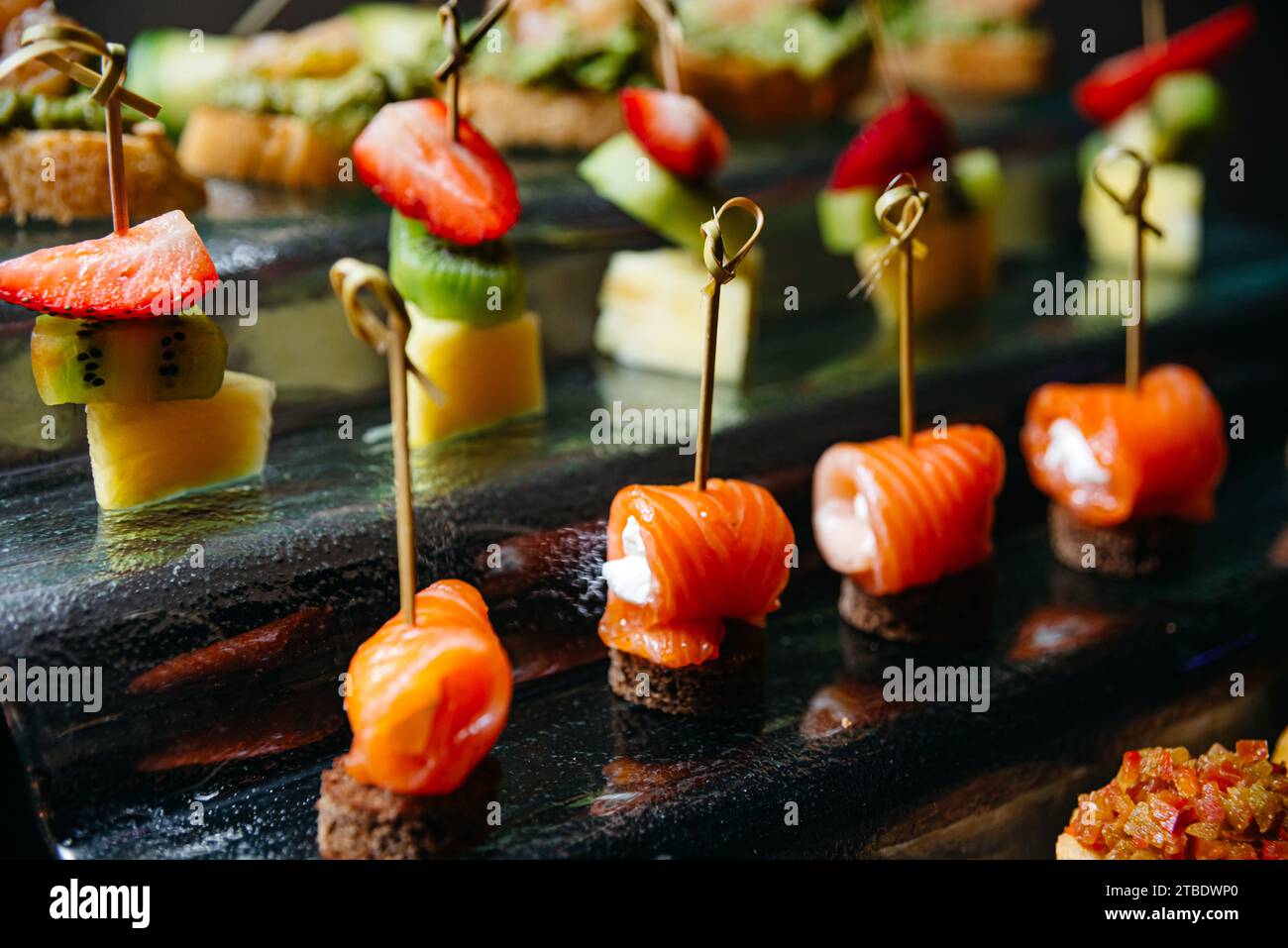 Fruit canape made from strawberries, kiwi, pineapple. Salmon canapes ...