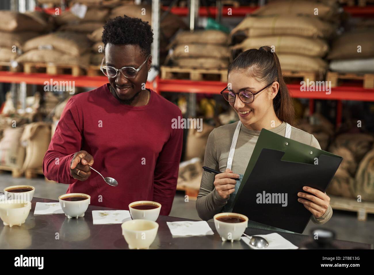 Portrait of two smiling young people discussing coffee varieties during ...