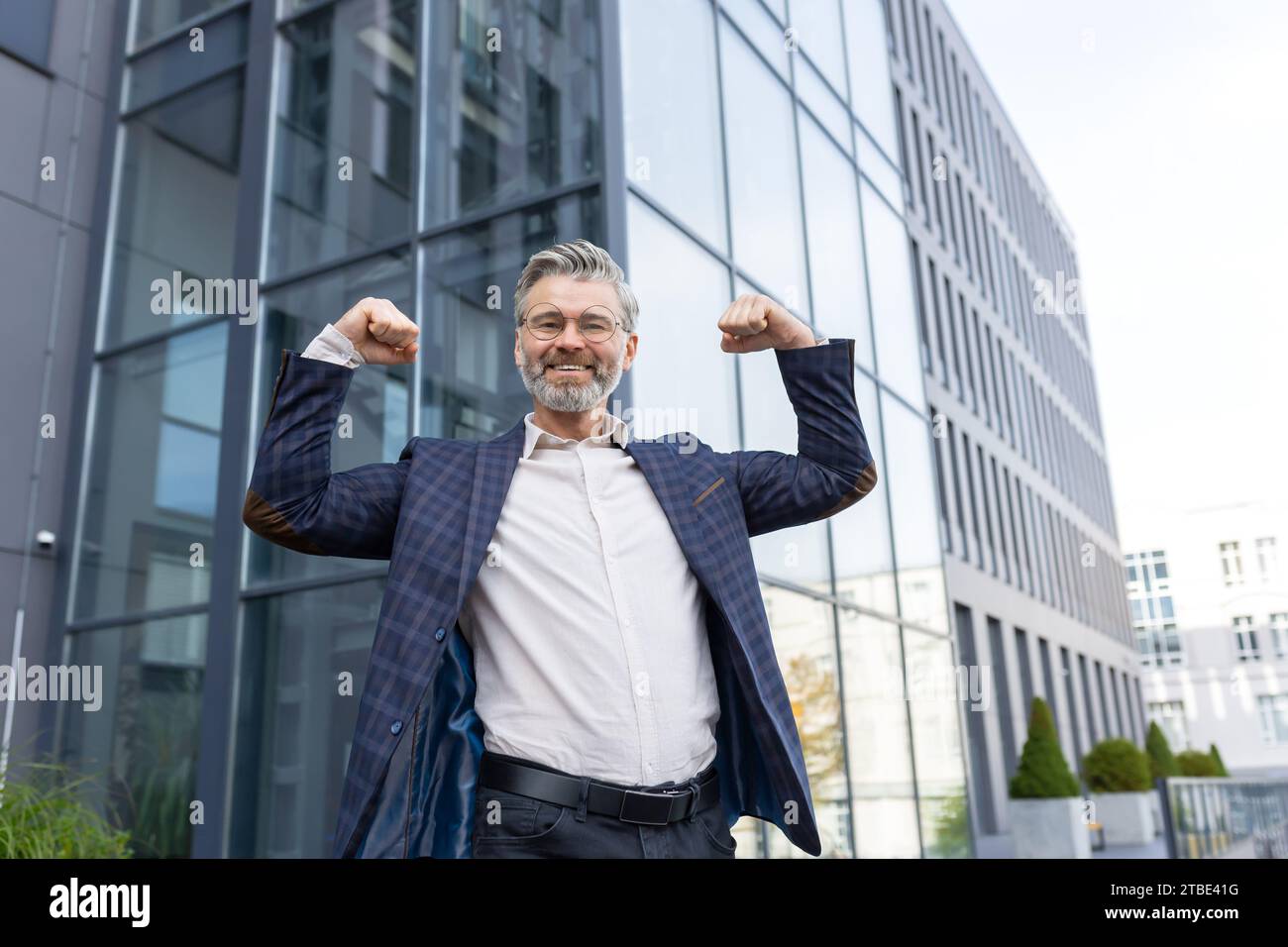 Successful senior businessman in suit standing in front of office ...