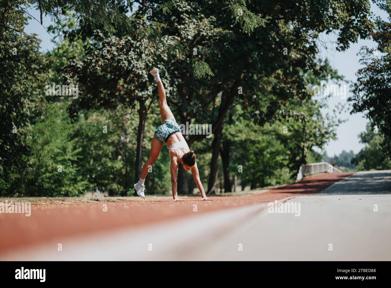 Active Caucasian sports girl competes in cartwheeling outdoors ...