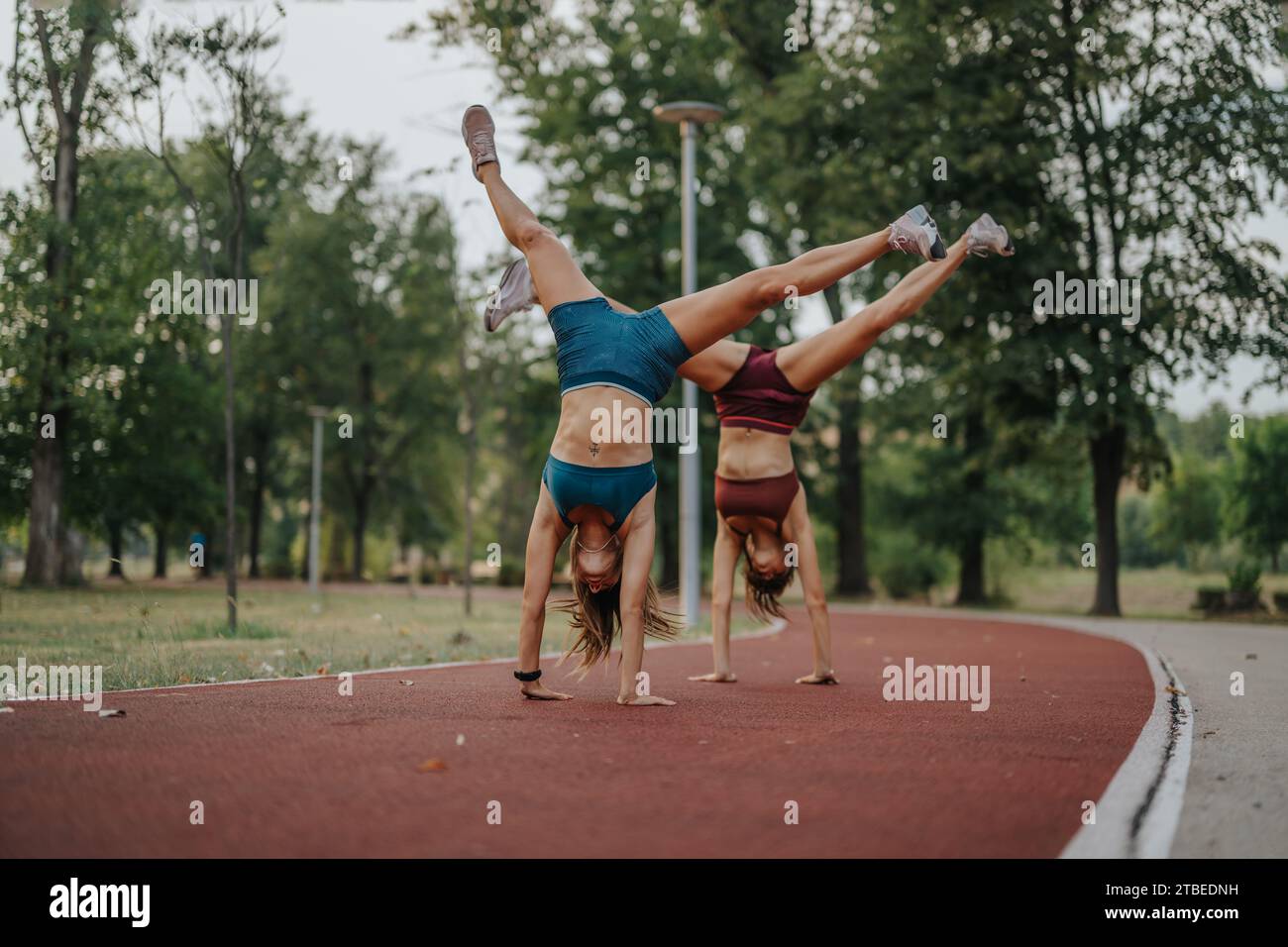 Two athletic sisters performing 360-degree flips in a park, showcasing ...