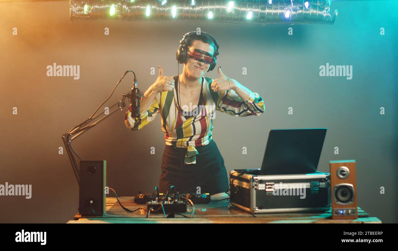 Disc jockey gives thumbs up while mixing music at techno party ...