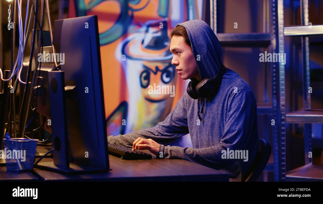 Happy asian hacker in graffiti painted hideout having burst of joy ...