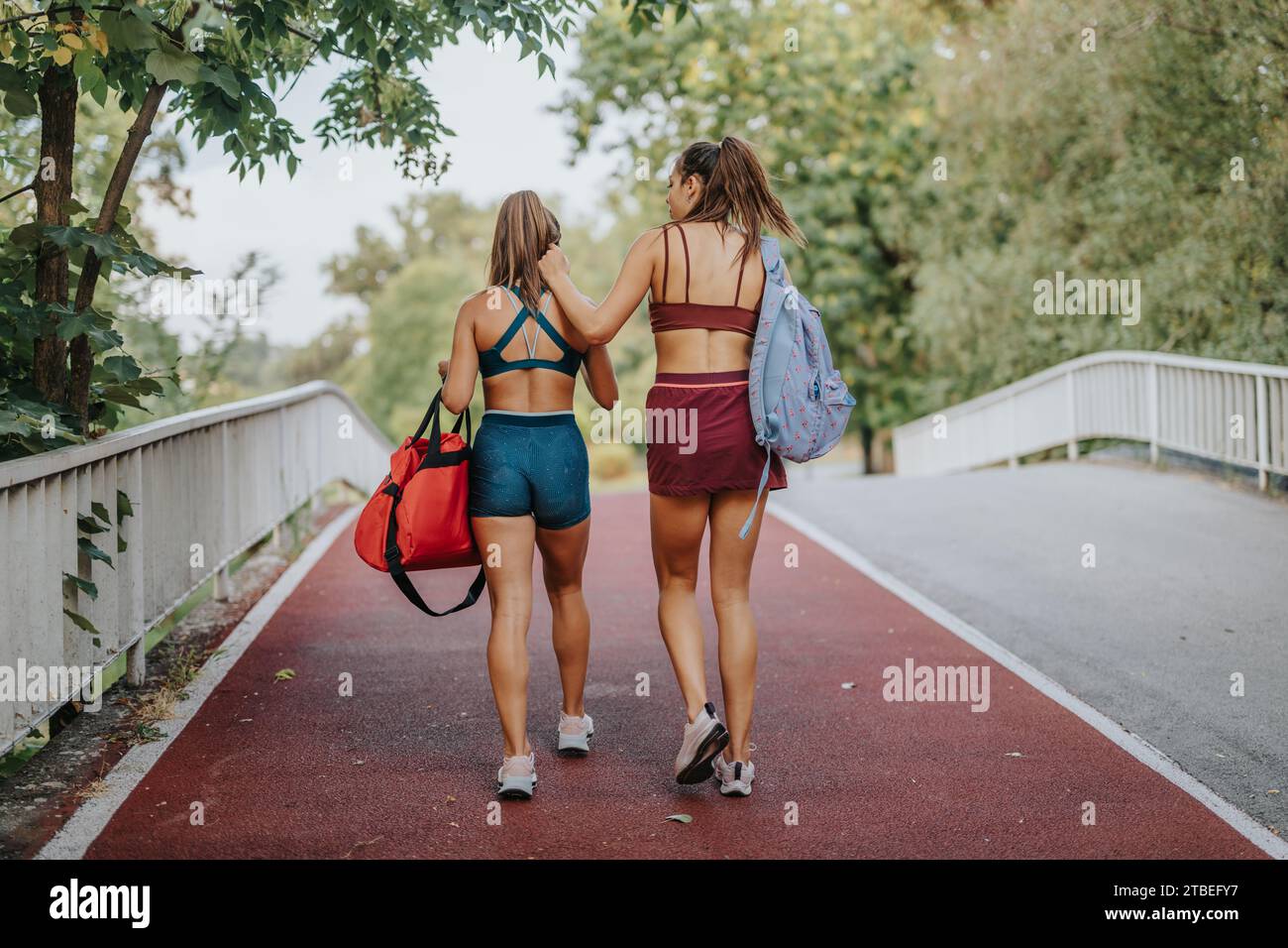 Motivated athletic girls walking home after a workout in a green park ...