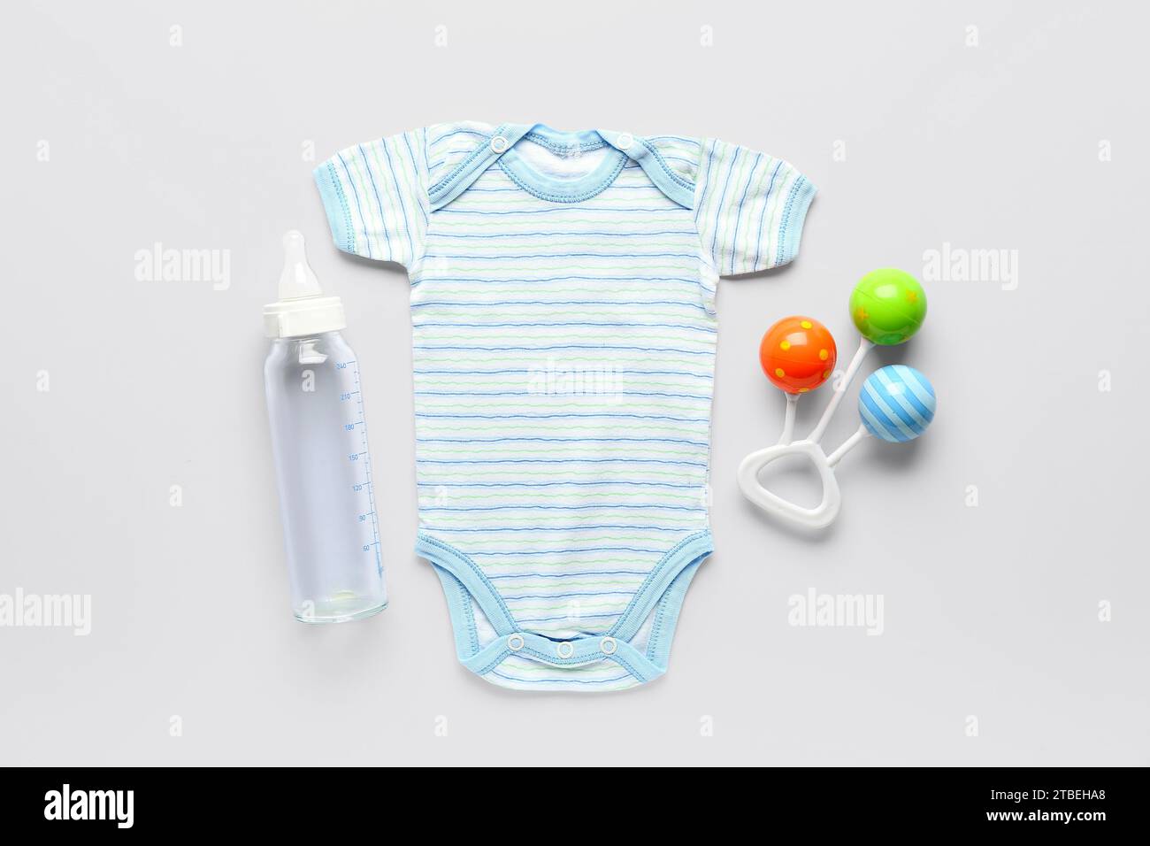 Cotton clothes with baby bottle and rattle on white background Stock ...