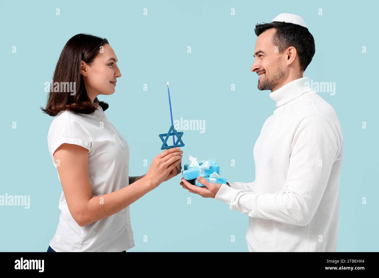 Lovely couple with David star, gift boxes and candle on blue background ...