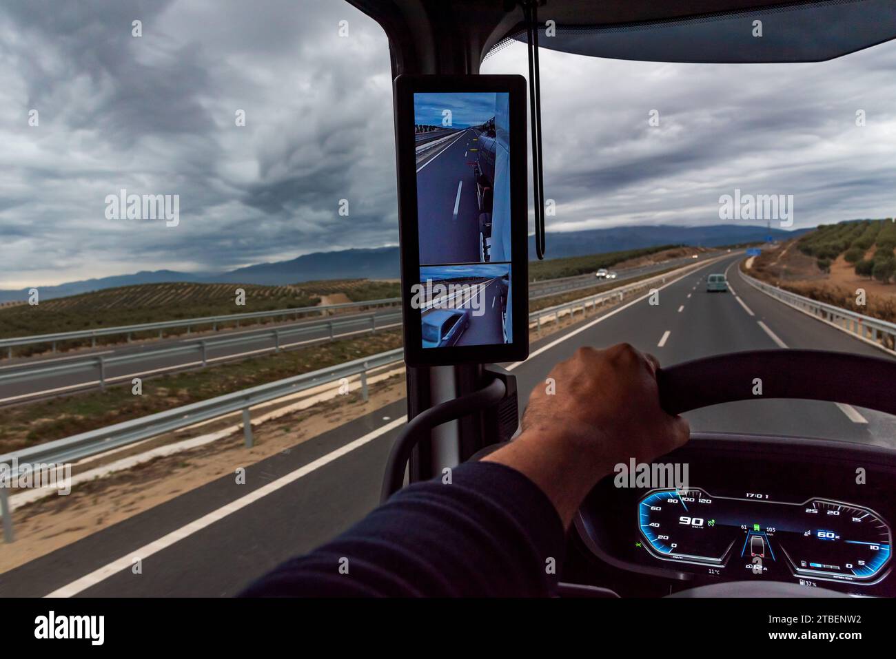 View from the driving position of a truck of a road with storm clouds ...