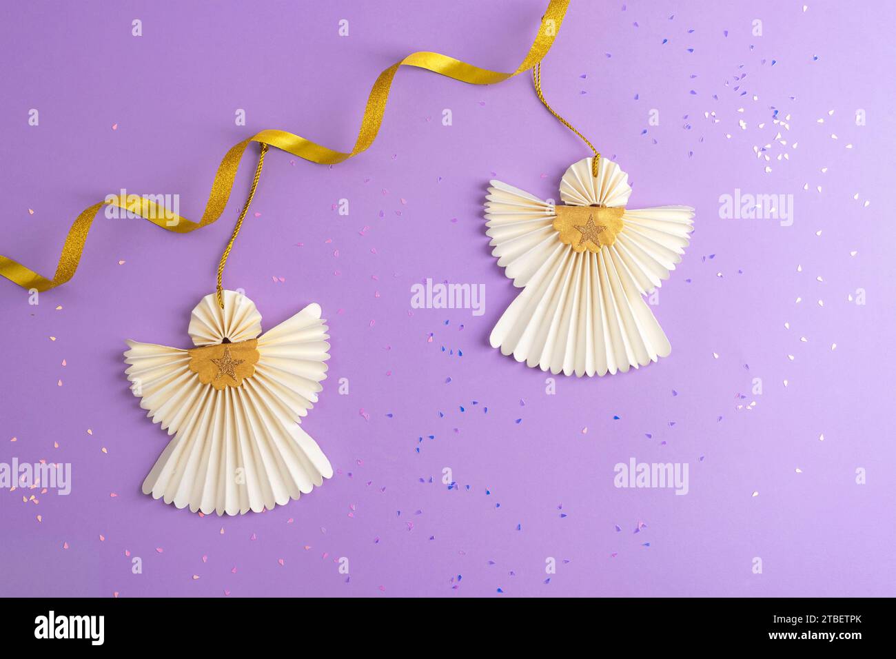 Two Christmas paper angels with golden tinsel on purple background ...