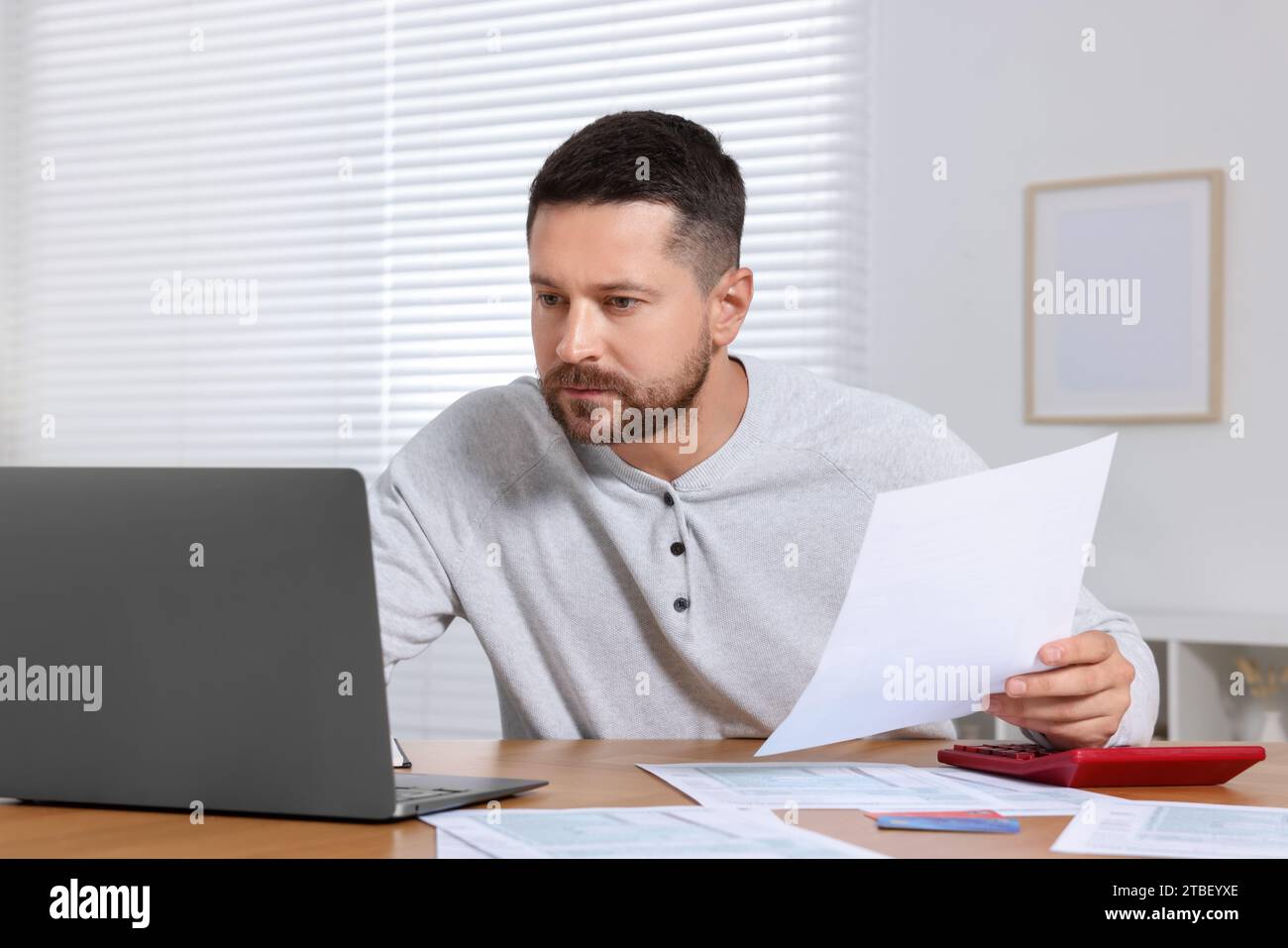 Man doing taxes at table in room Stock Photo - Alamy