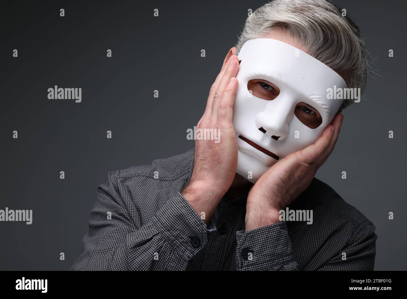 Multiple personality concept. Man in mask on dark grey background ...
