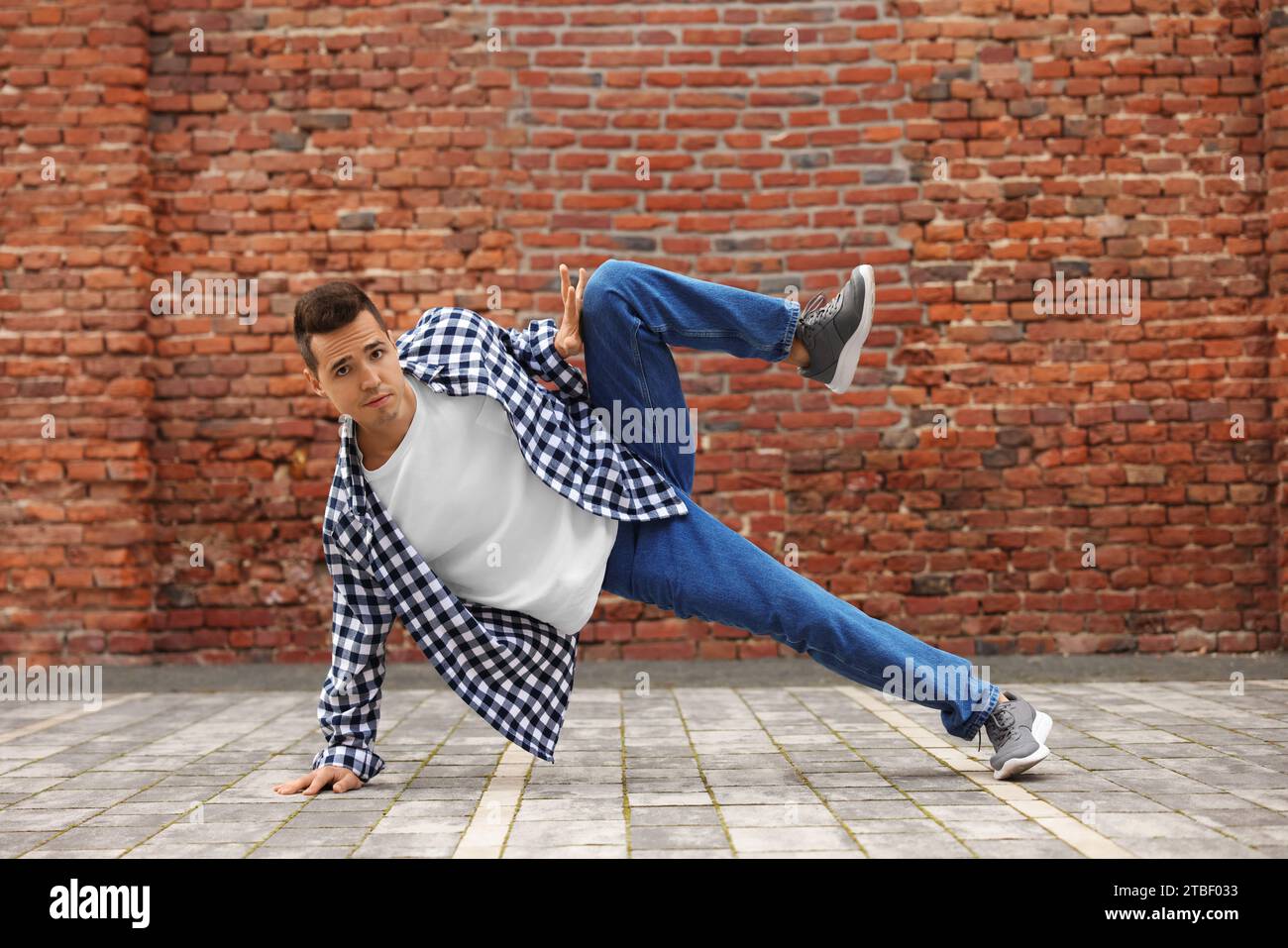 Man dancing hip hop near brick wall outdoors Stock Photo - Alamy