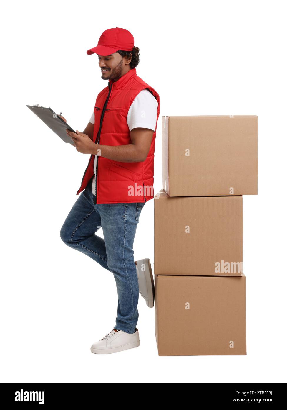 Happy young courier with stack of parcels and clipboard on white ...