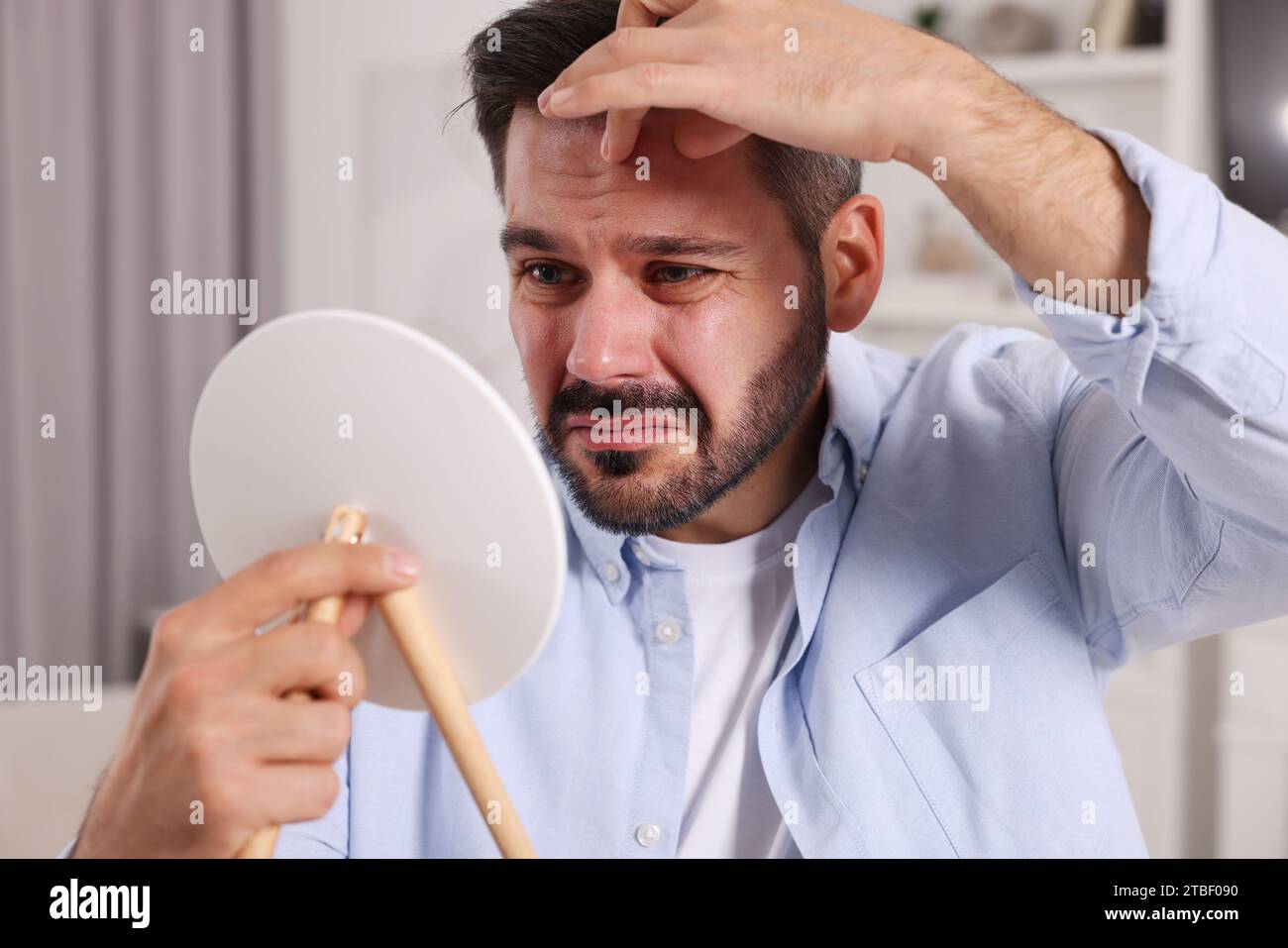 Confused man with skin problem looking in mirror at home Stock Photo ...