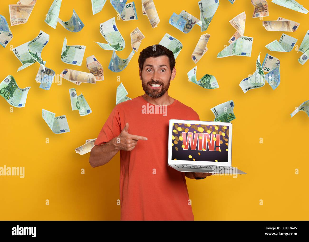 Betting. Happy man pointing at laptop with word Win! under money shower ...
