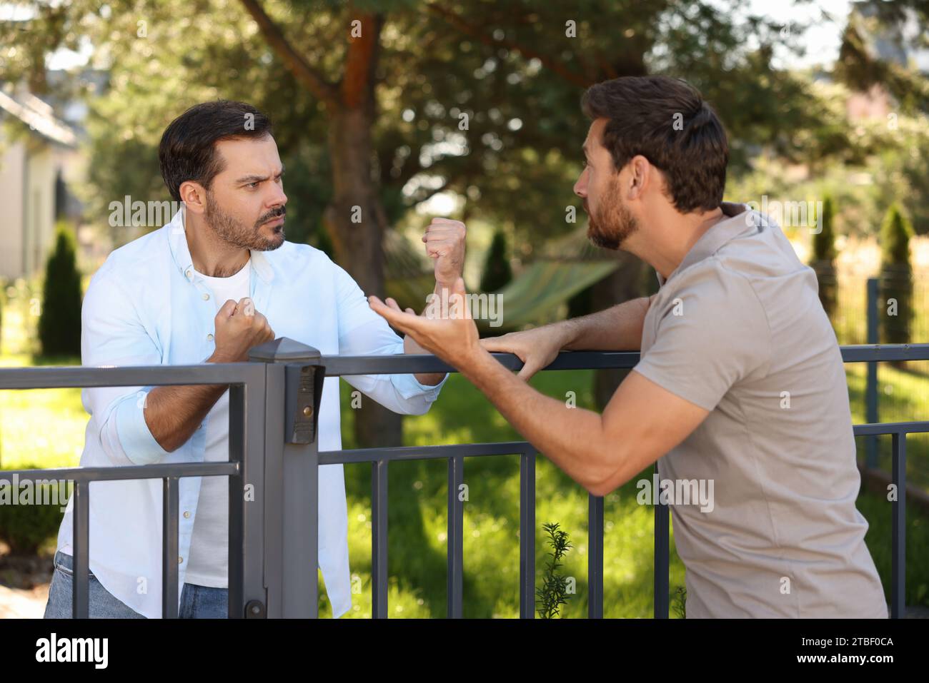 Angry neighbours having argument near fence outdoors Stock Photo - Alamy