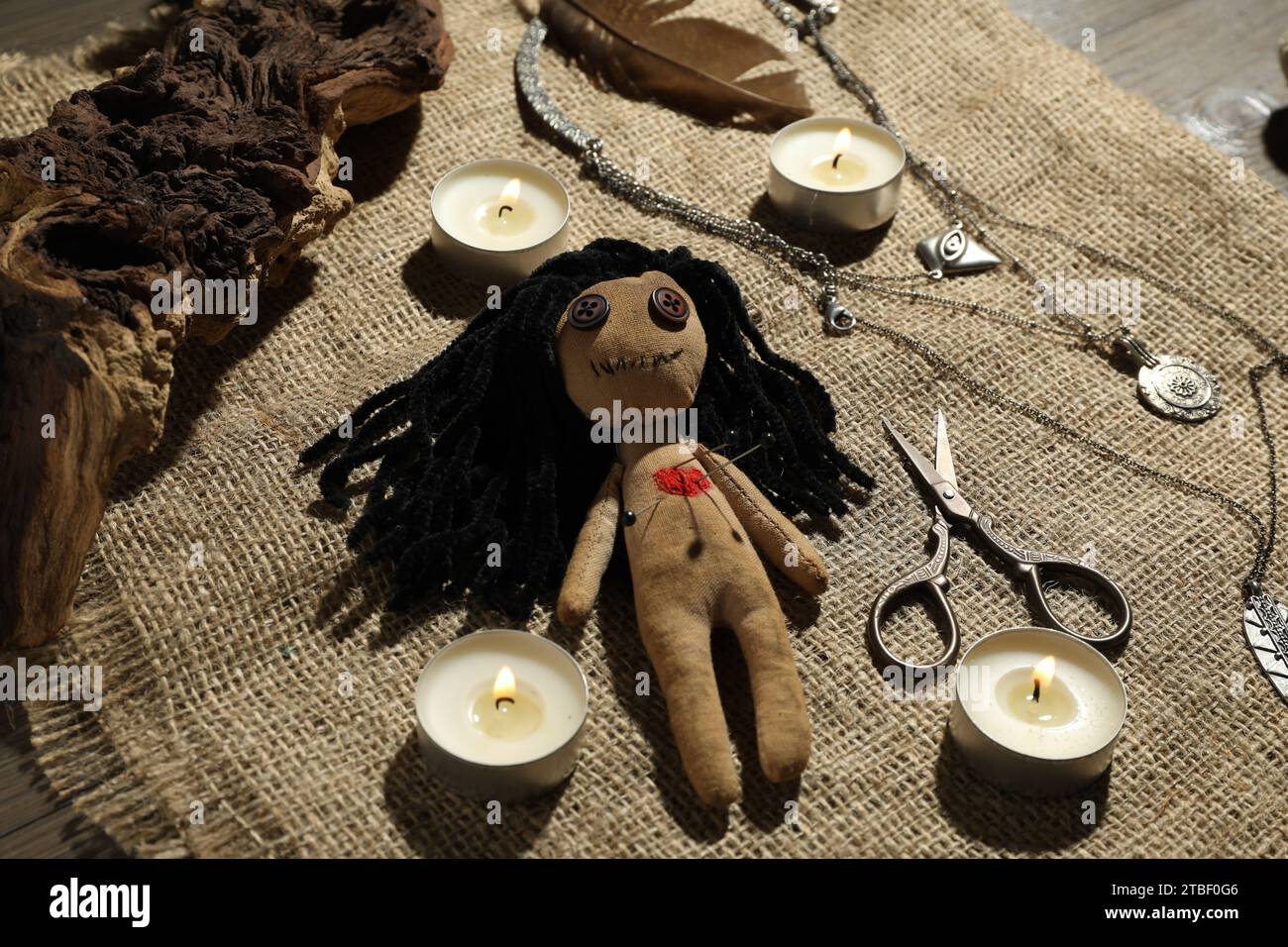 Voodoo doll with pins surrounded by ceremonial items on burlap fabric ...