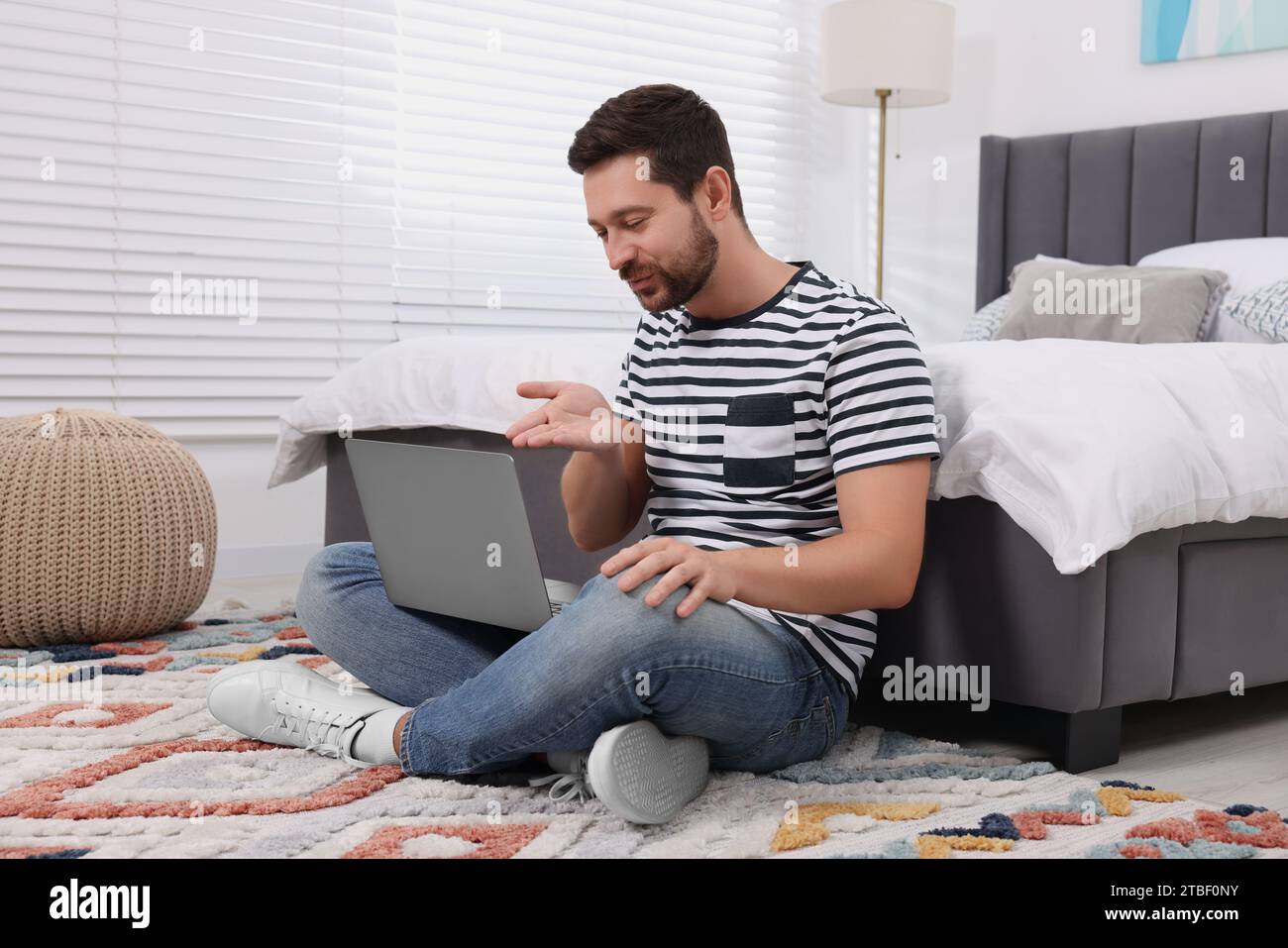 Happy man blowing kiss during video chat via laptop in bedroom. Long ...