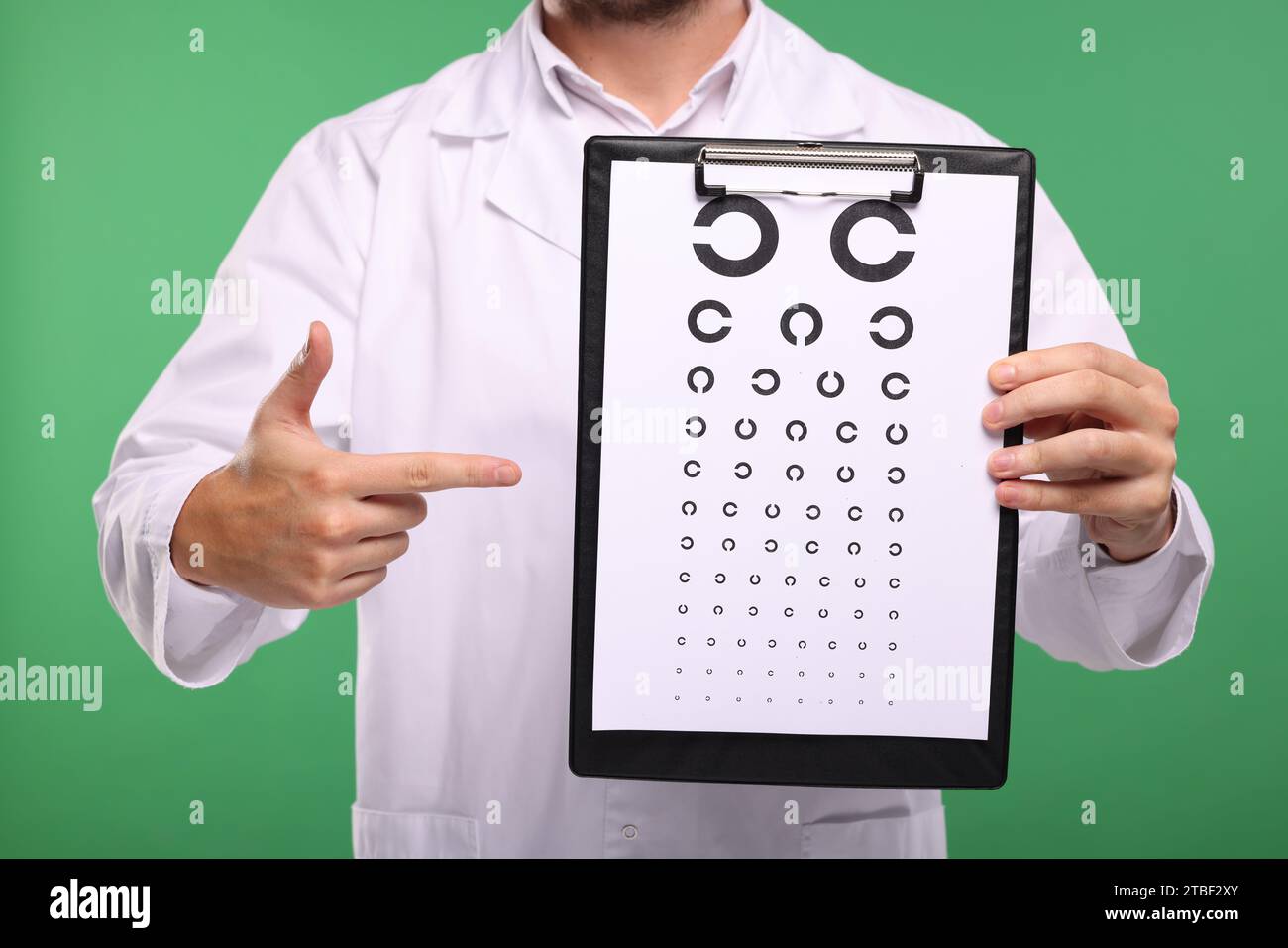 Ophthalmologist pointing at vision test chart on green background ...