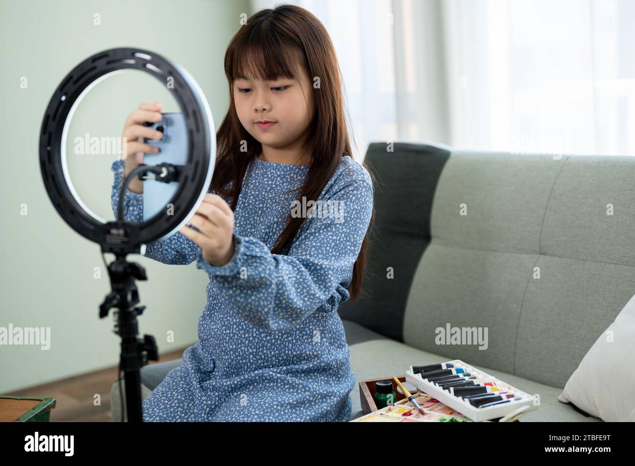 An adorable young Asian girl recording her video or live streaming ...