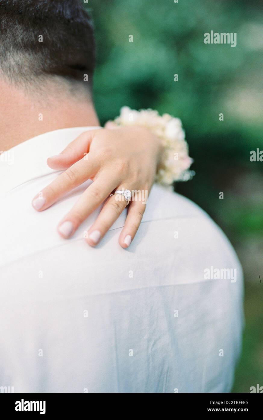 Bride hand hugs groom shoulder. Back view. Cropped Stock Photo - Alamy