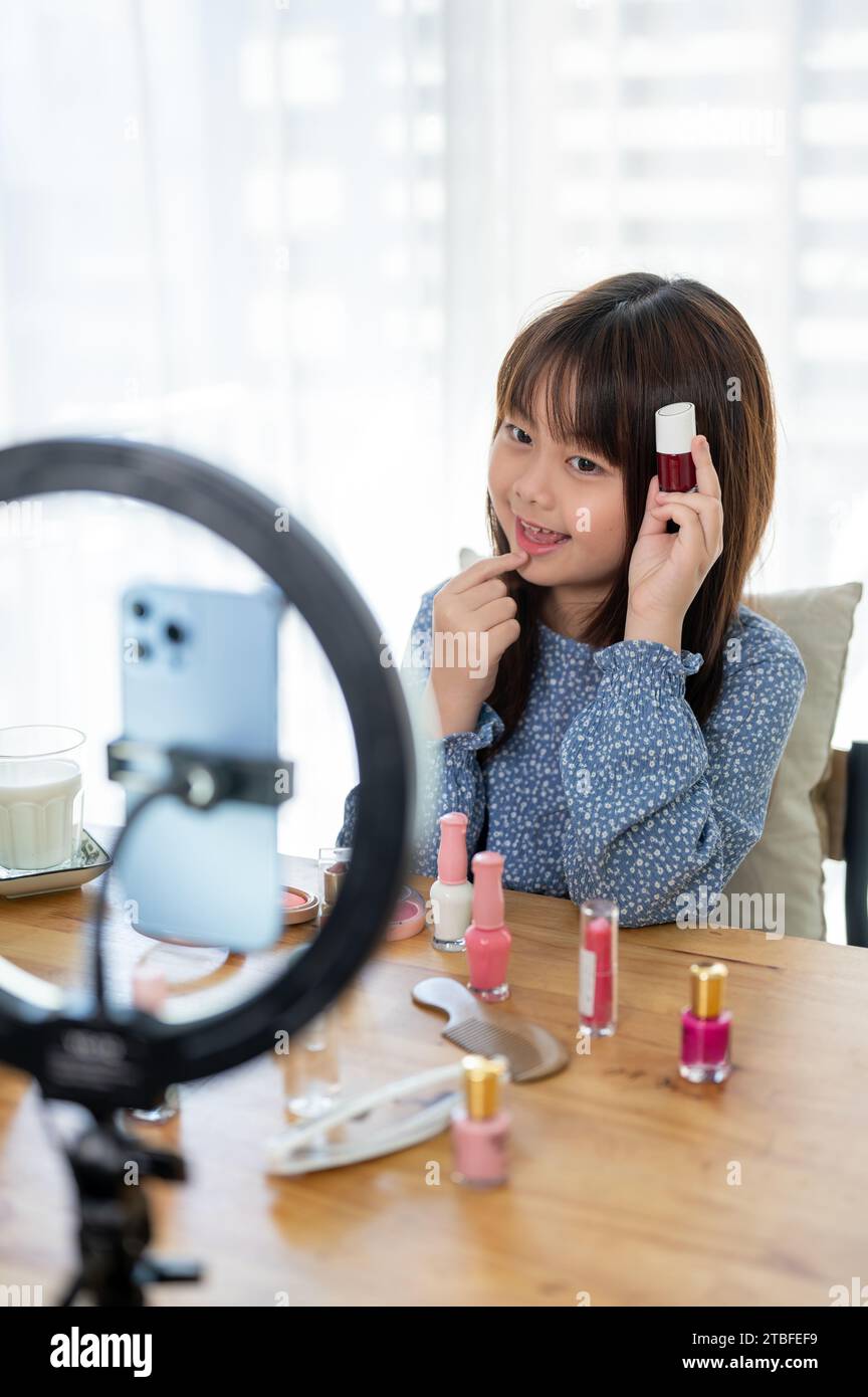 A pretty and talented young Asian girl is showing kid cosmetic products ...
