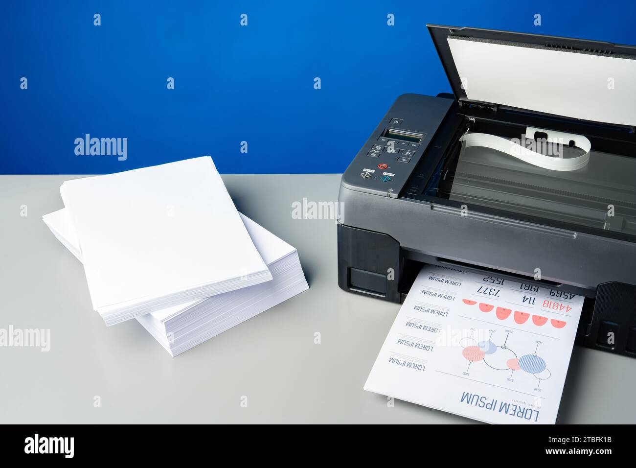 Laser printer on desk against blue background Stock Photo - Alamy