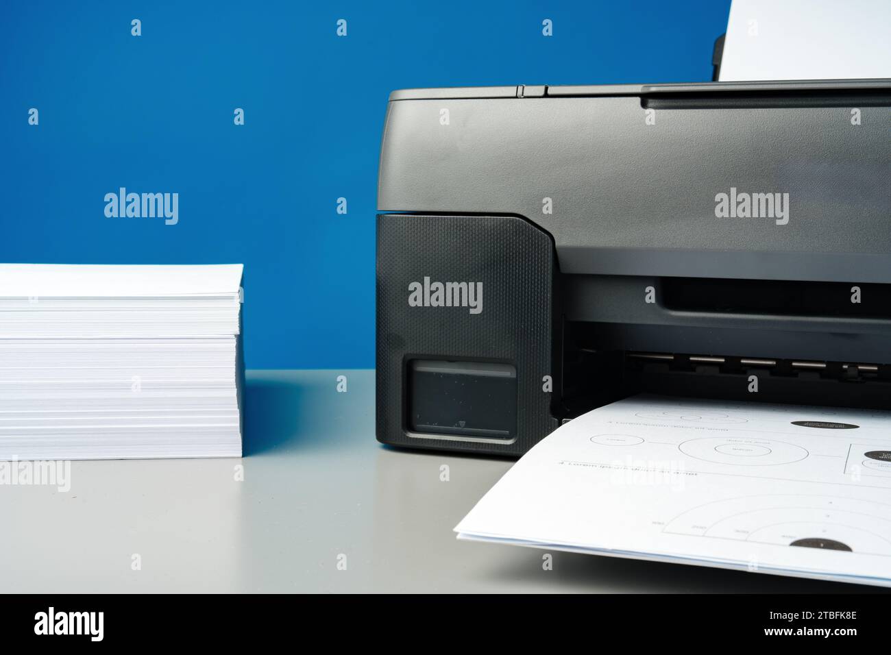Laser printer on desk against blue background Stock Photo - Alamy