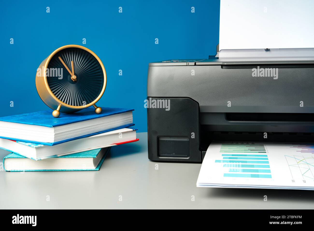 Laser printer on desk against blue background Stock Photo - Alamy