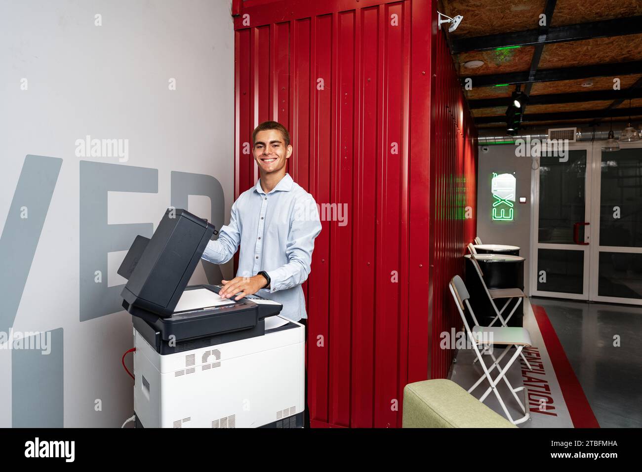 Positive young man using printer in the modern office Stock Photo - Alamy