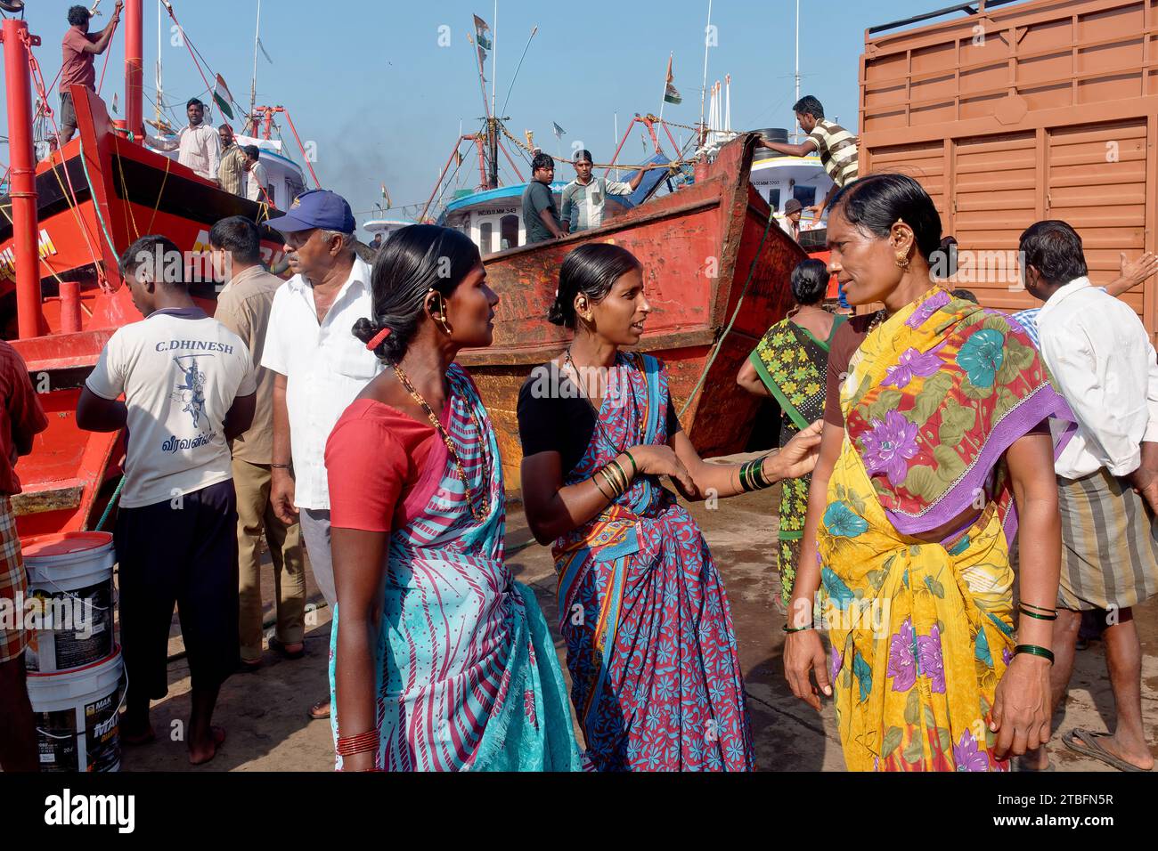 Three Indian women purchasing fish at the busy Old Port in Mangalore ...