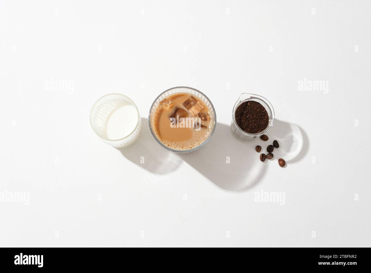 A cup of milk, a cup of milk coffee and a beaker containing coffee ...