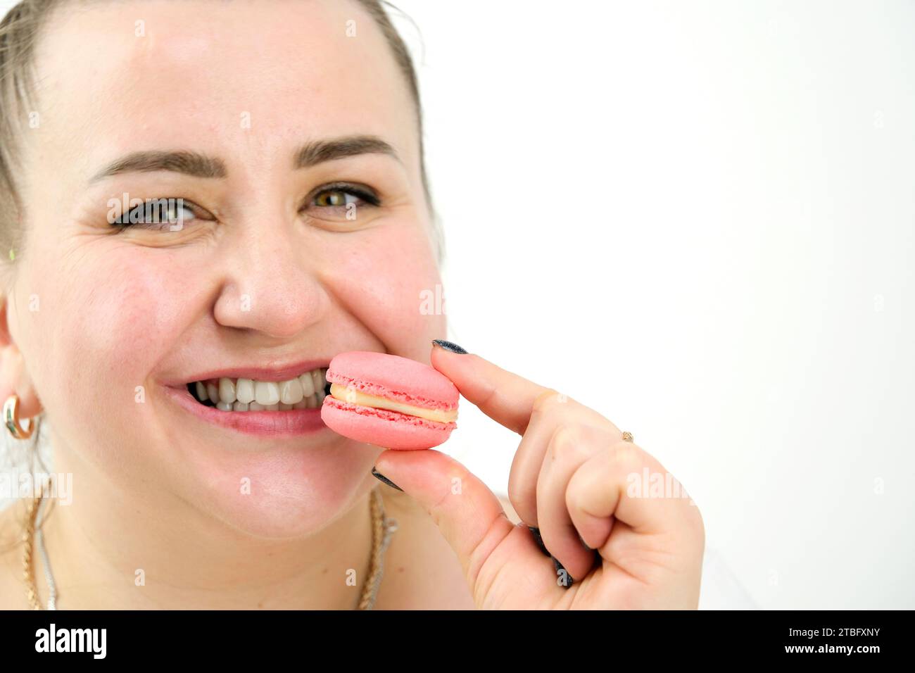 satisfied and happy woman eating macaroons on white background space ...