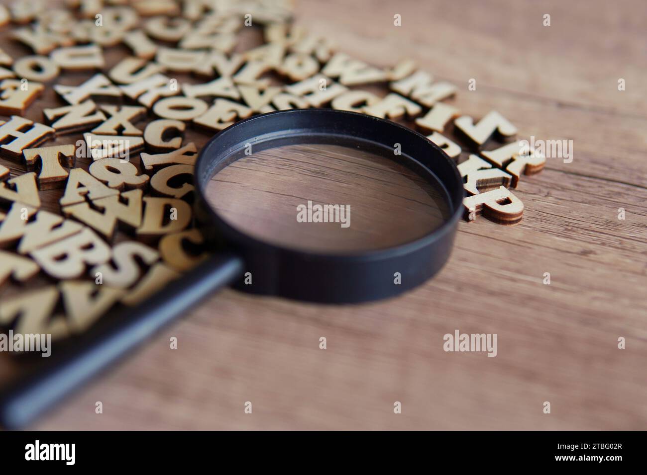 Magnifying glass with scattered alphabet letters on the table. Copy ...