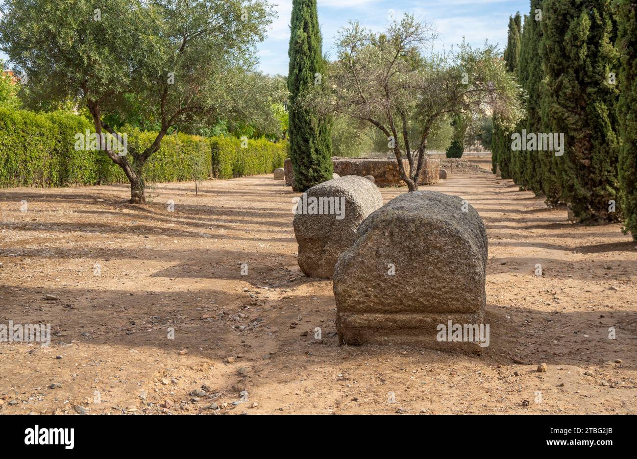 Dirt road between stone Roman tombstones and mausoleums and cypress ...