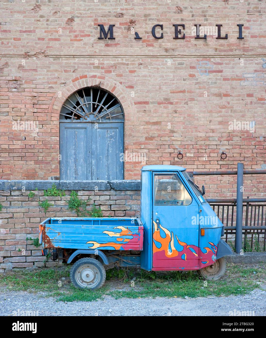 three wheeled car Piaggio Ape in front of an old decayed slaughterhouse ...
