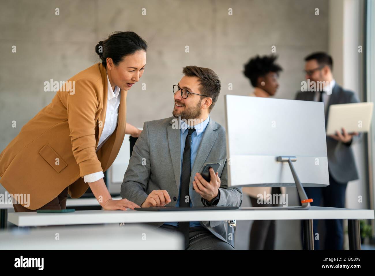 Senior business manager talking with experienced colleague while using ...