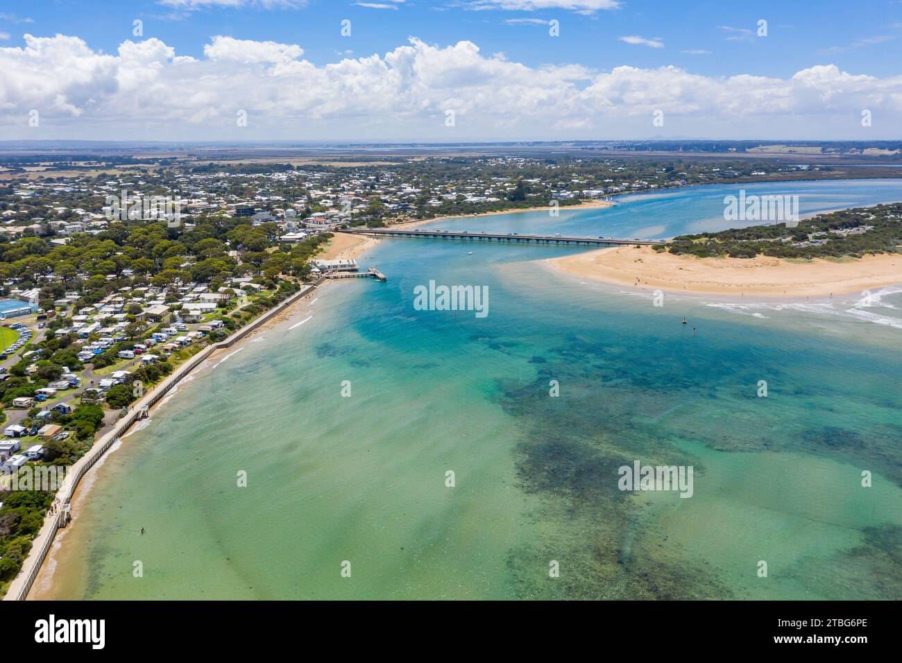 Aerial view of a wide river flowing under a bridge joining two coastal ...