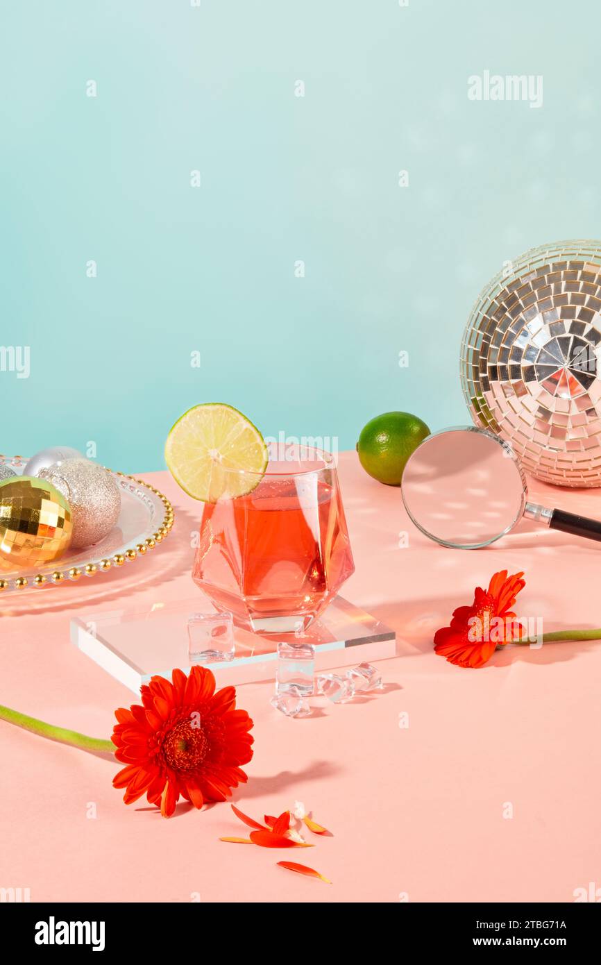 A glass containing a clear red liquid with a slice of lemon is placed ...