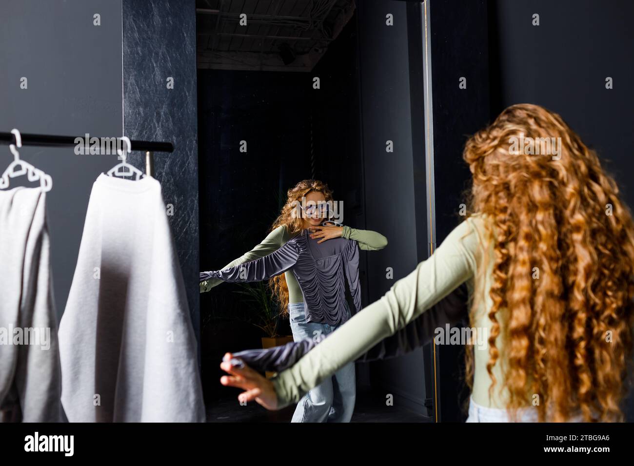 Young beautiful woman choosing clothes at fitting room. Shopping ...