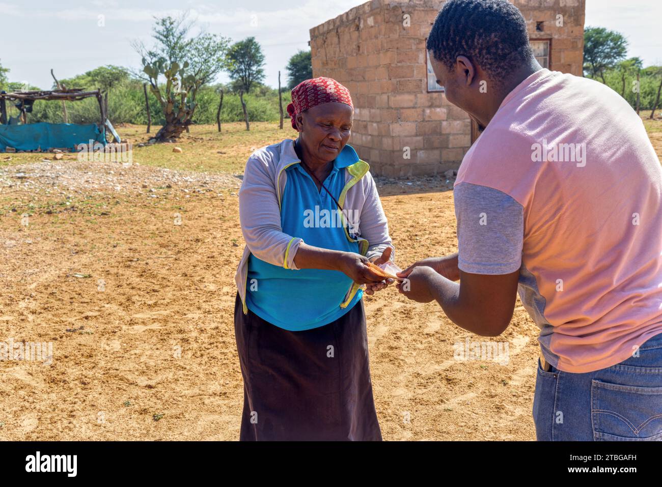 village african woman receiving money from a young man in the yard ...