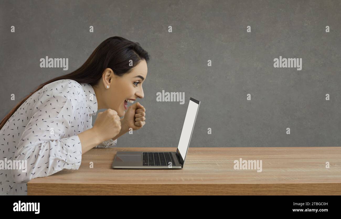 Joyful emotional woman looking at laptop and shouting with happiness ...