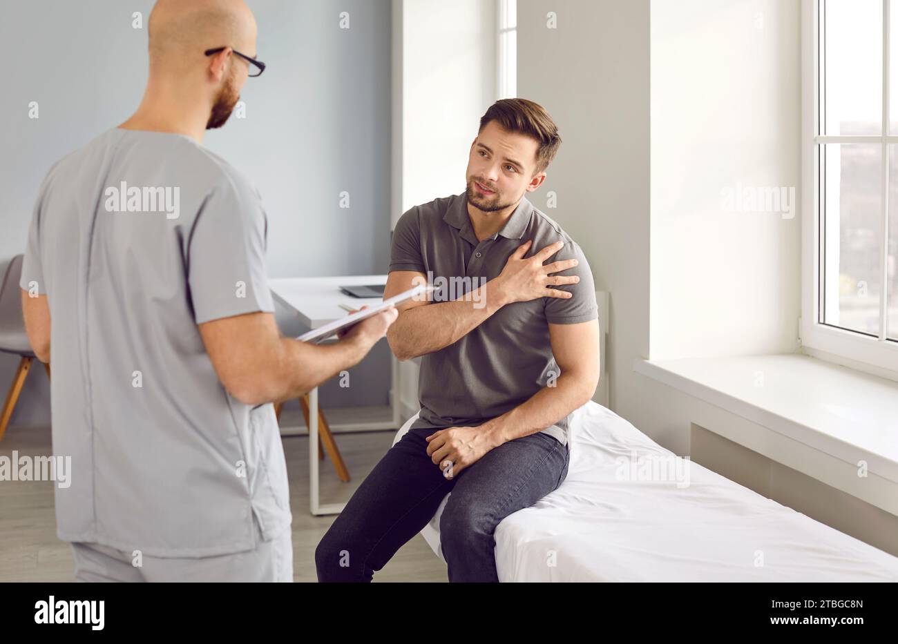 Man sitting on an examination bed and telling his doctor about pain in ...