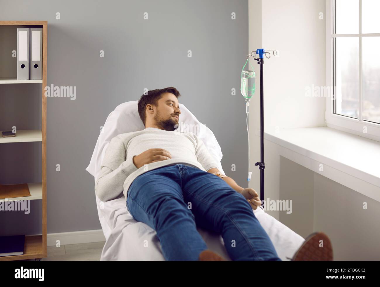 Young man receiving medication infusion through an intravenous drip at ...