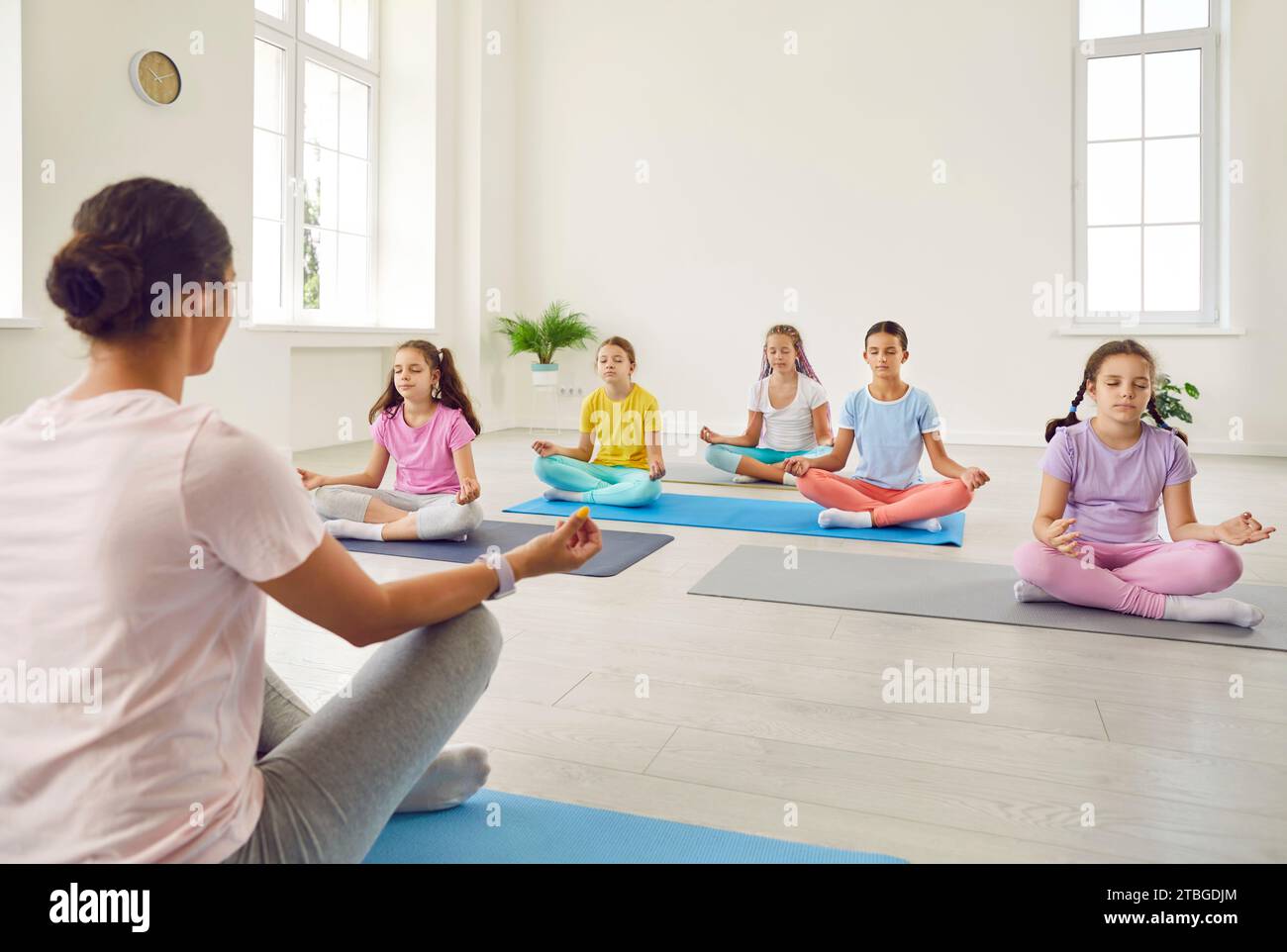 Group of girls having a yoga lesson, sitting on the floor in the lotus ...