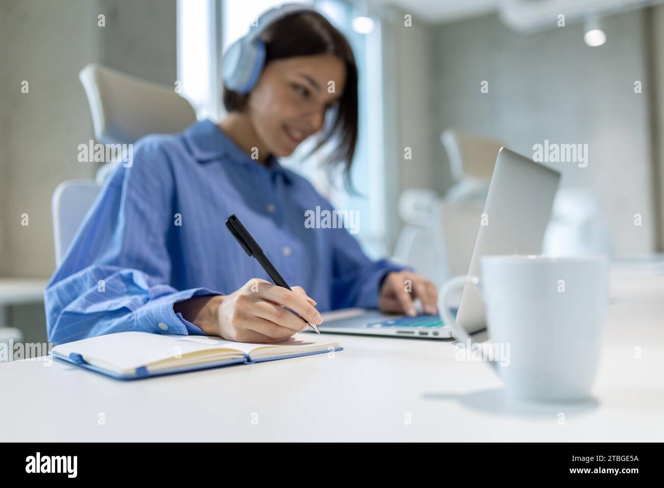Smiling corporate employee in the headphones seated at the portable ...