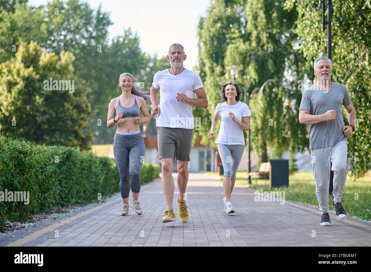 Healthy group of people jogging in park, enjoying friend time at jogging park while running ...