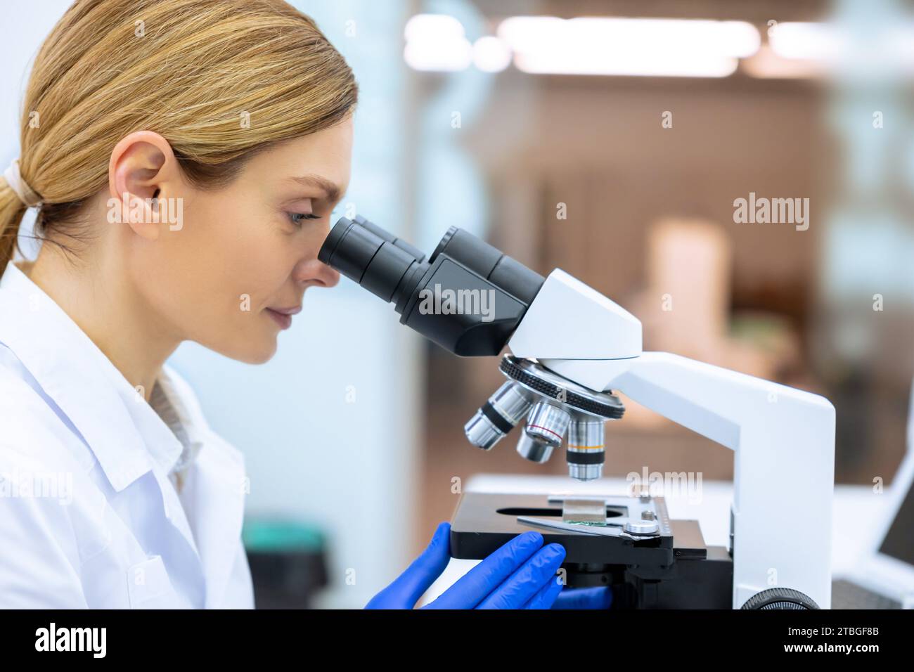 Side view portrait of blonde woman scientist looking biochemical cell ...